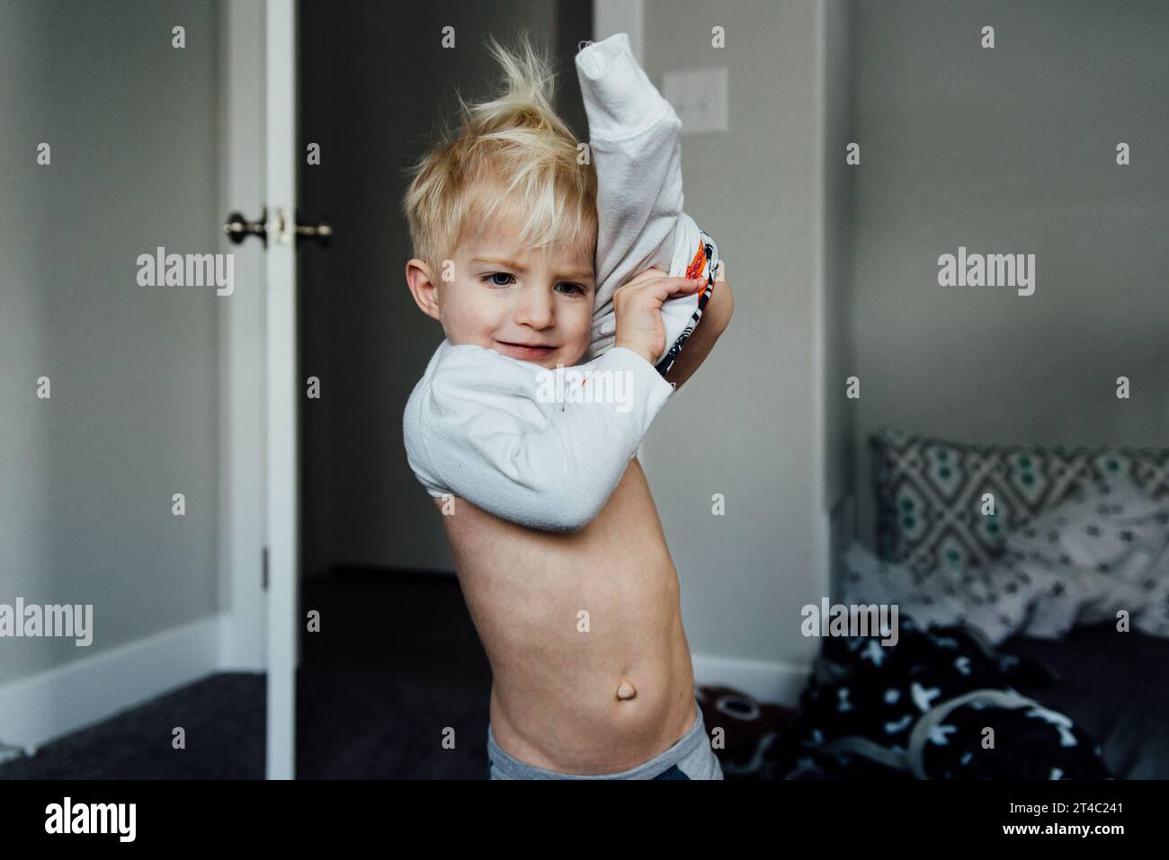 Little blonde boy with messy hair tries to dress himself in mess Stock ...