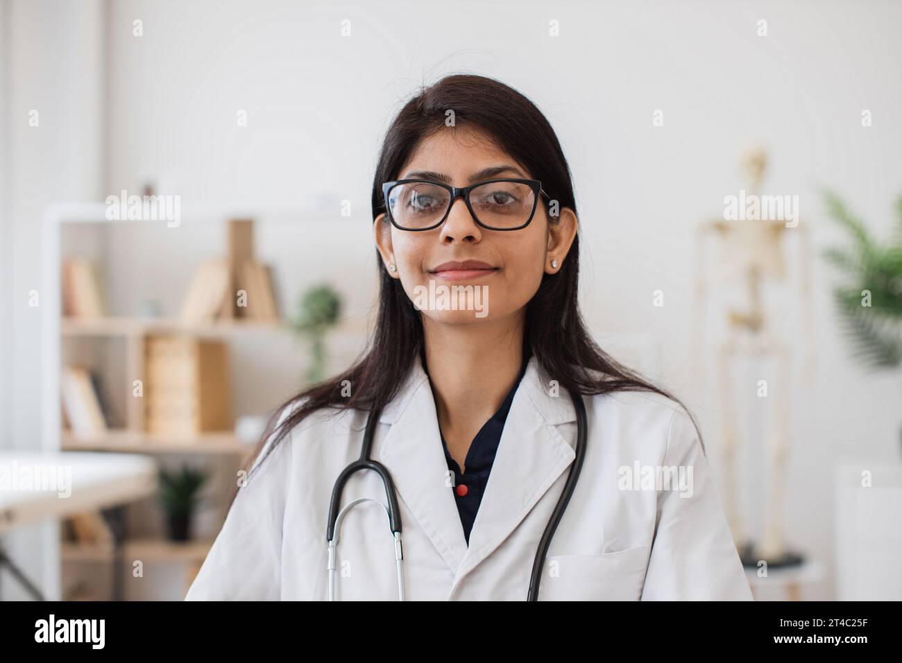 Female general practitioner in medical gown sitting and keeping hand on ...