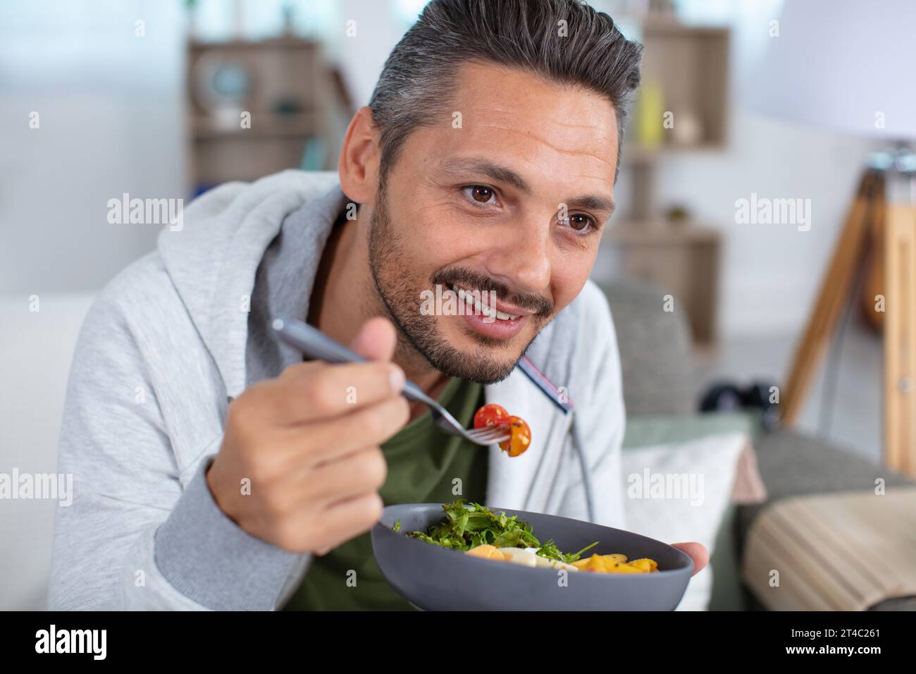 a smiling man eating a salad Stock Photo - Alamy