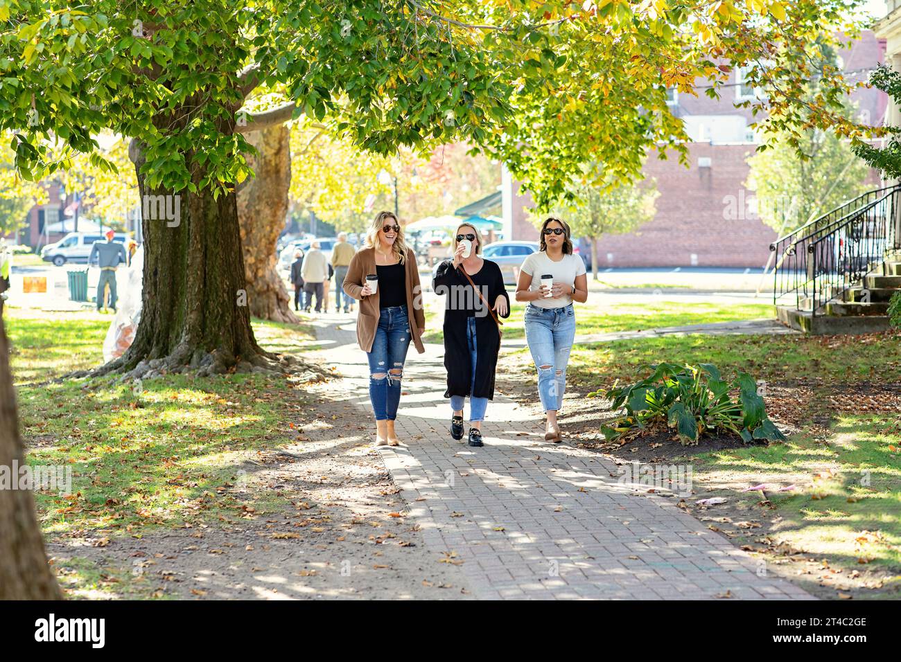 Three women walking down Main Street drinking coffee Stock Photo - Alamy