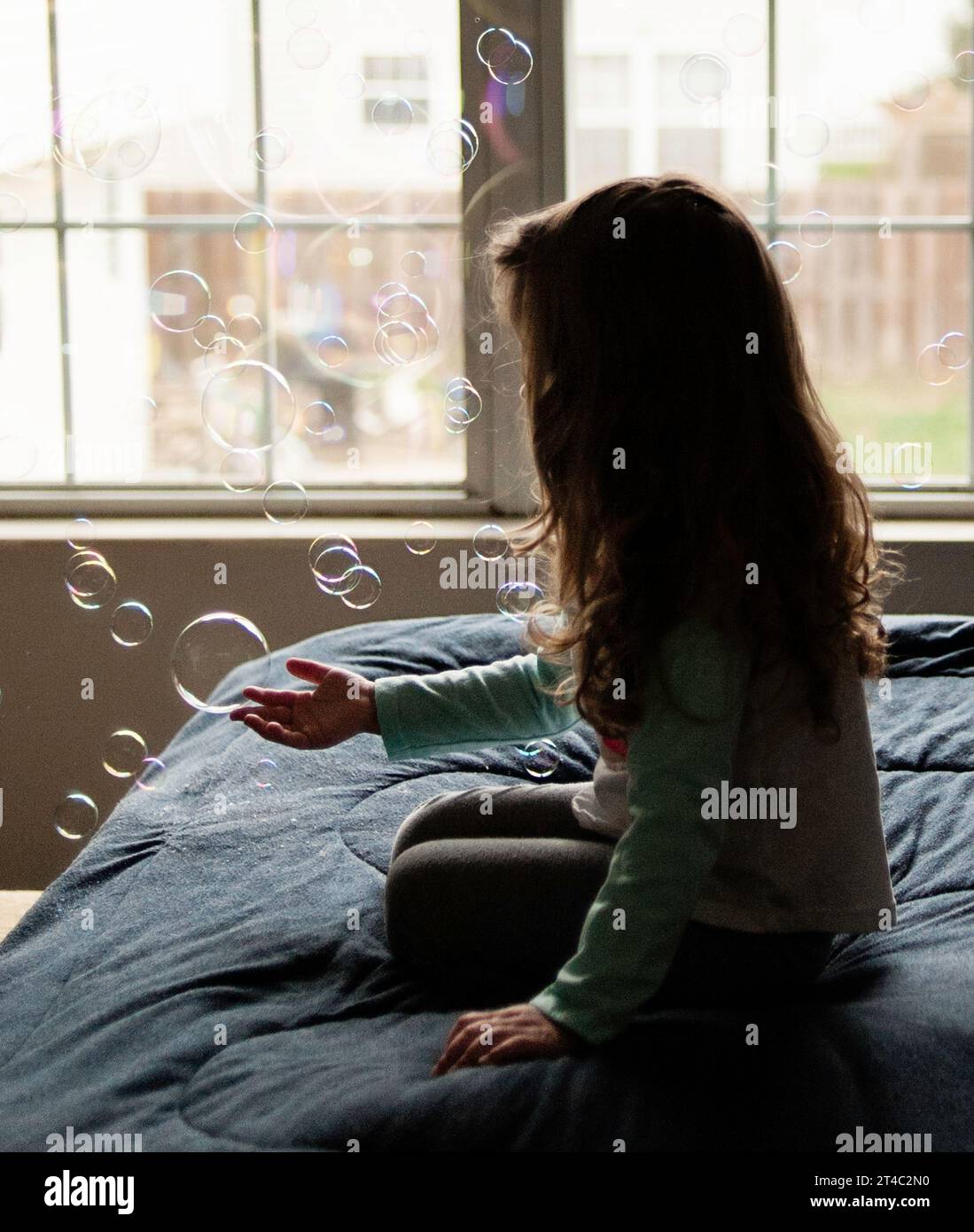 Little girl catching bubbles in bedroom Stock Photo - Alamy