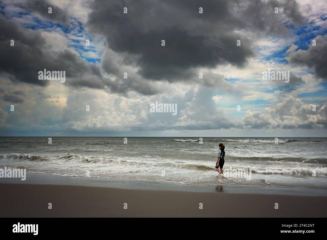 Young child standing in the ocean during cloudy storm Stock Photo - Alamy