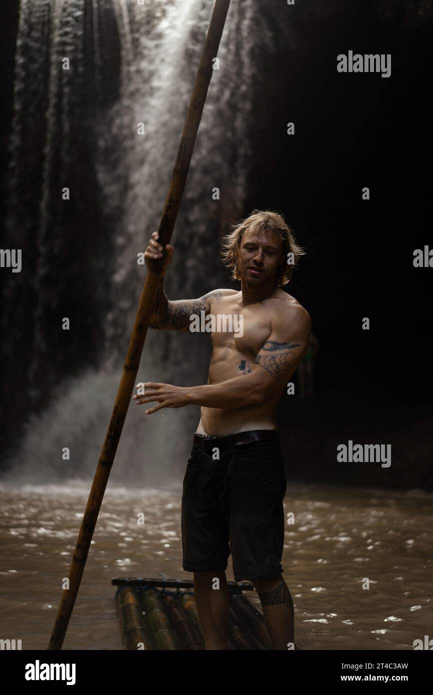 Man on a bamboo raft on a mountain river near a waterfall, Bali Stock ...