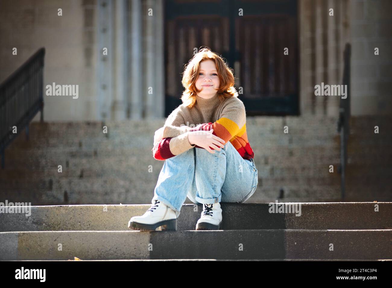 Pretty smiling teen girl sitting on cathedral steps, backlit Stock ...