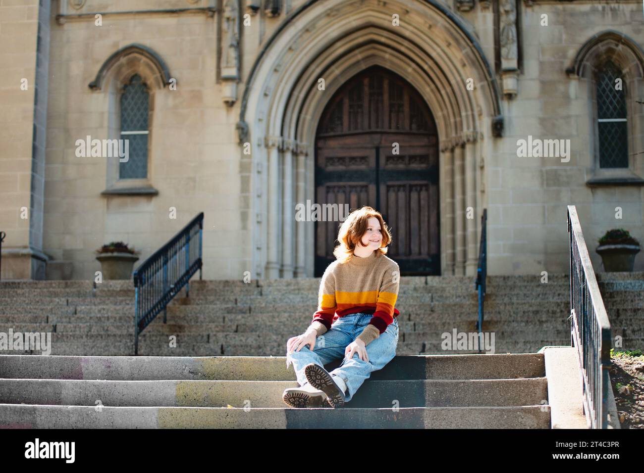 Pretty teen girl sitting on cathedral steps, backlit Stock Photo - Alamy