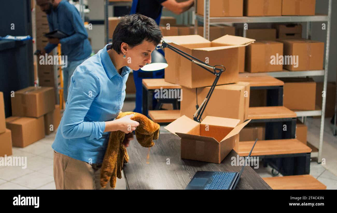 Female entrepreneur taking goods from storehouse racks and putting them ...