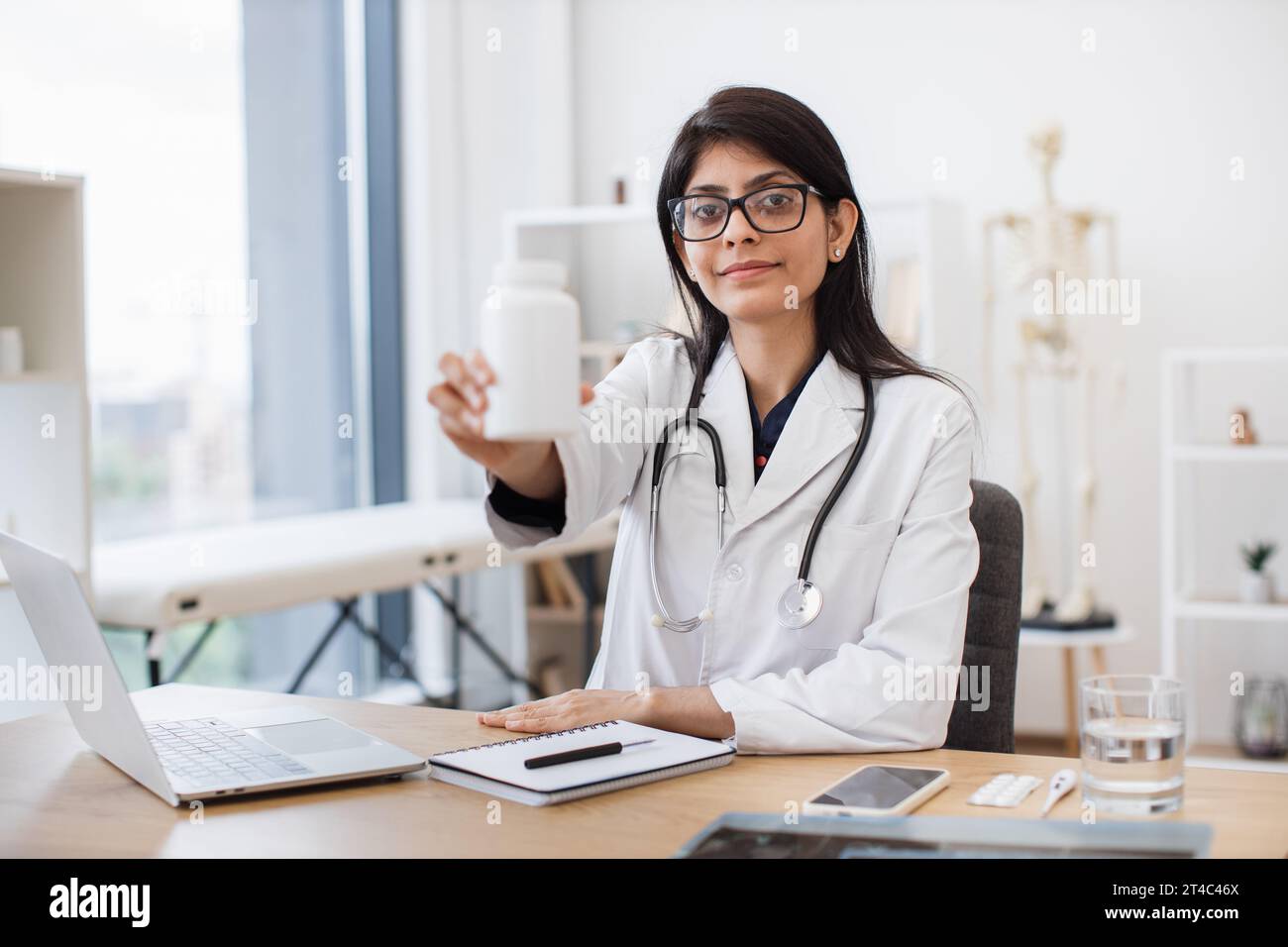 Thoughtful hindu female in medical white coat showing oral medication ...