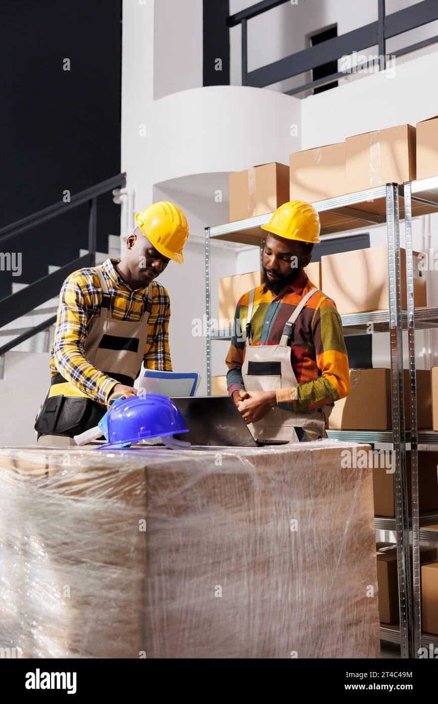 Logistics managers analyzing inventory and comparing data on laptop and ...