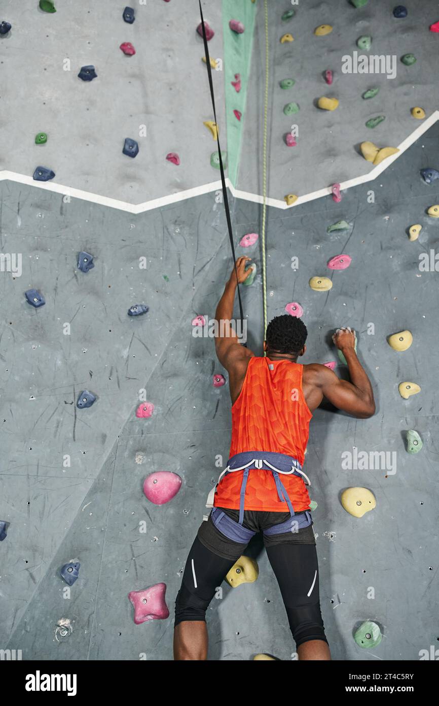 strong young african american man with alpine harness and safety rope ...
