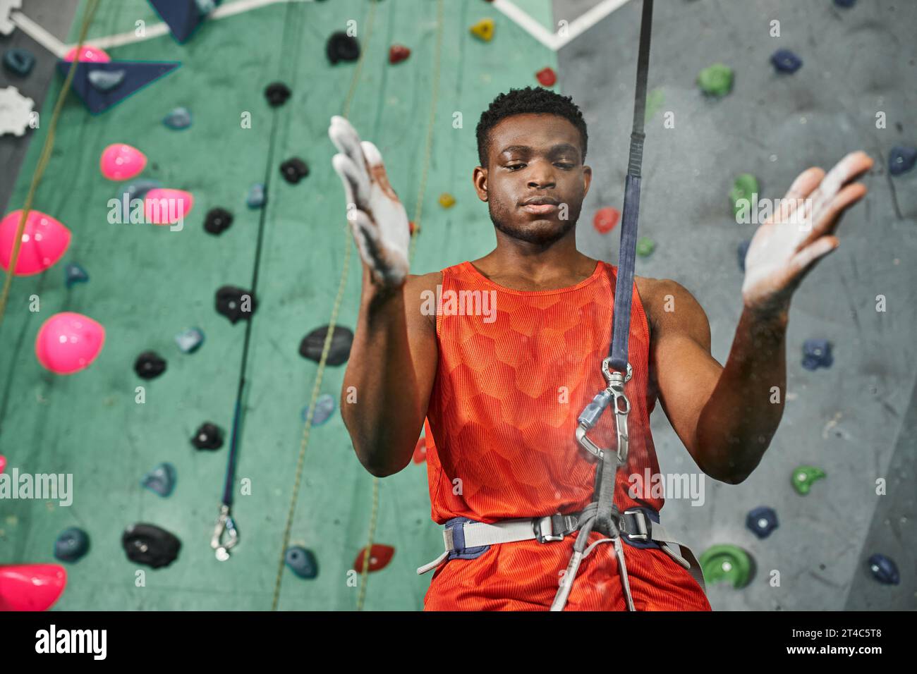 good looking african american man in orange shirt with safety rope ...