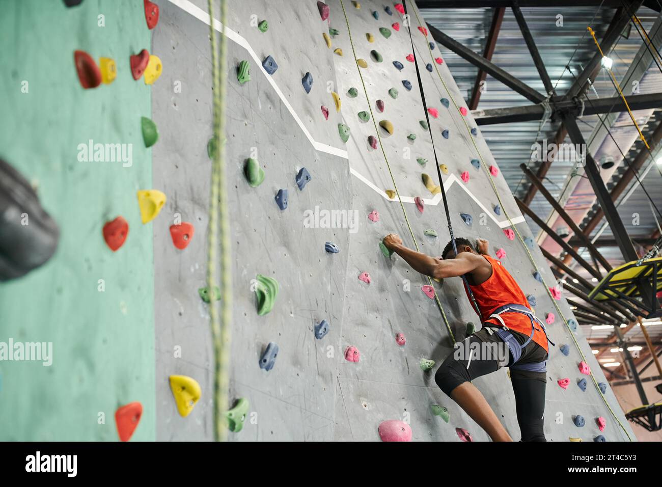 sporty young african american man in orange shirt ascending up ...