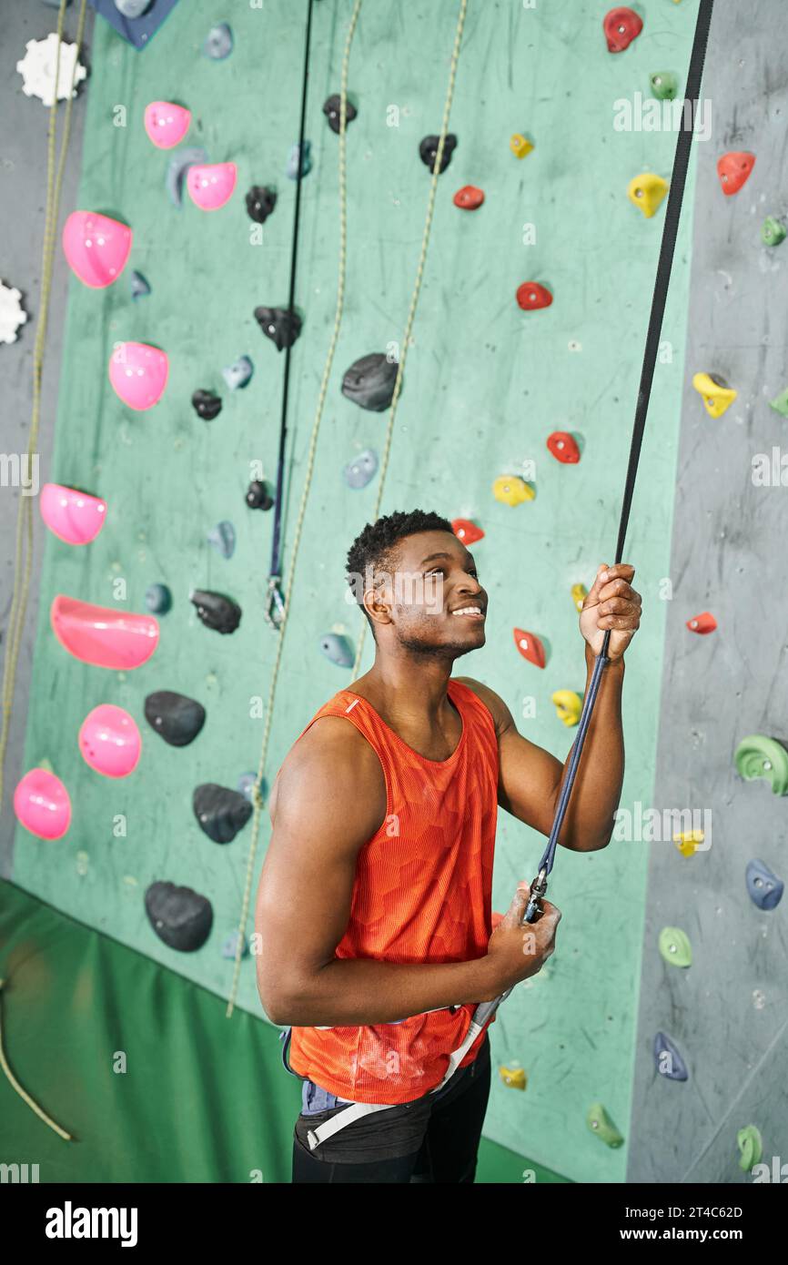 vertical shot of handsome smiley african american man using climbing ...