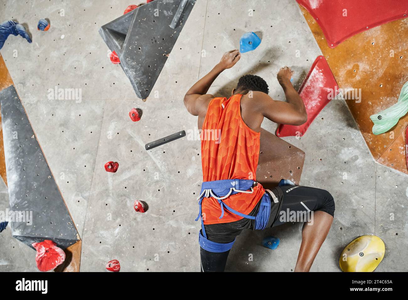 athletic young african american man with alpine harness ascending up ...