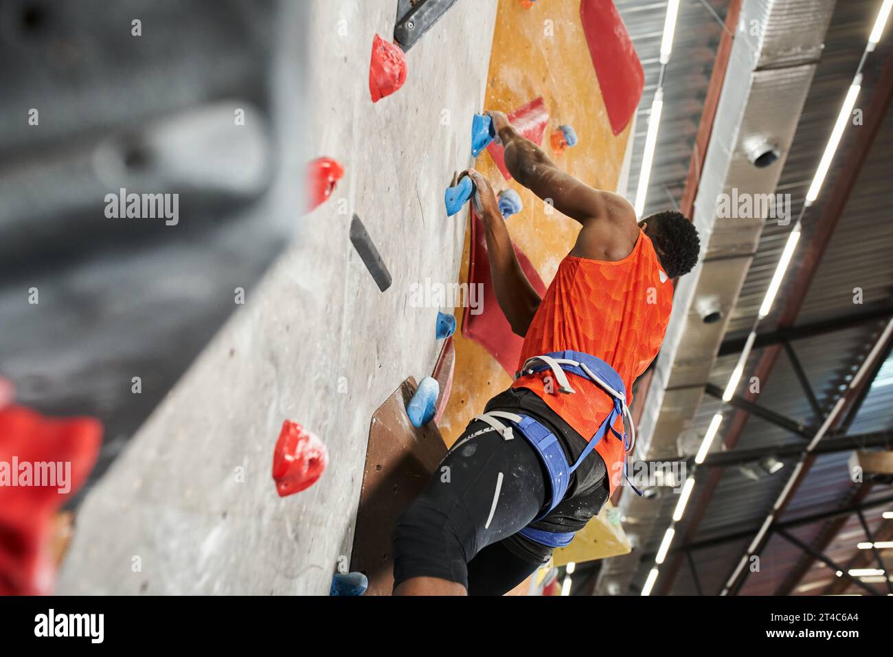 muscular african american man climbing up rock wall with alpine harness ...