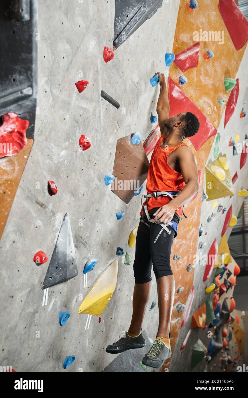 vertical shot of young african american man hanging on his fingertips ...
