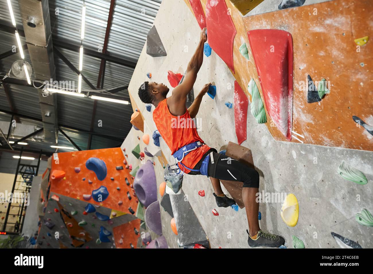 handsome african american man in orange shirt posing in profile while ...