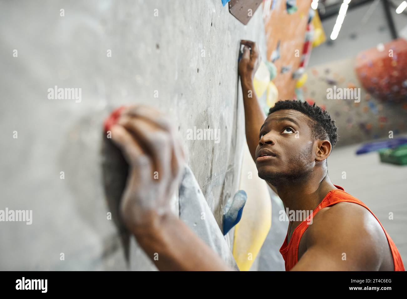 good looking young african american man climbing up bouldering wall and ...
