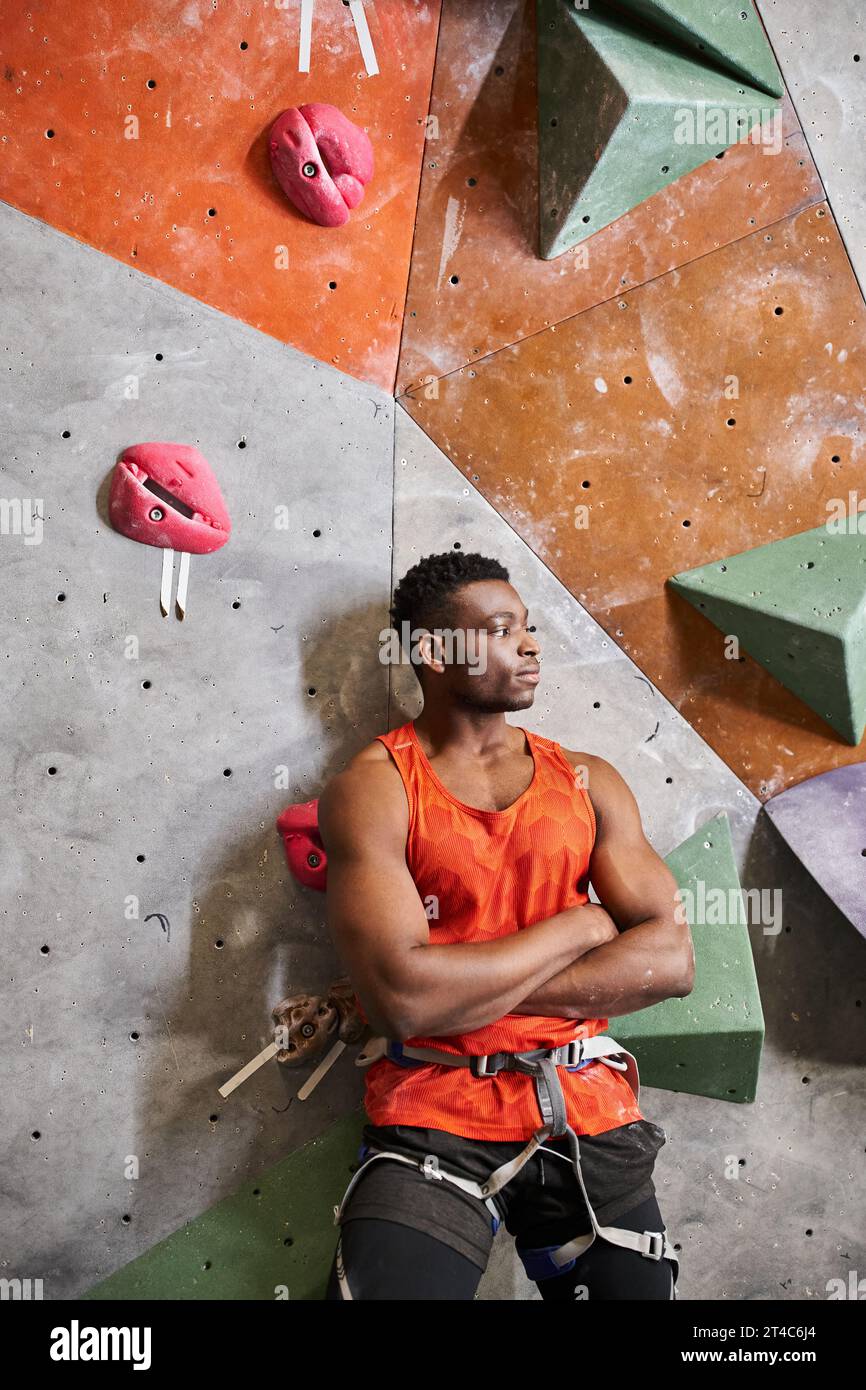 sporty african american man posing next to climbing wall with arms ...
