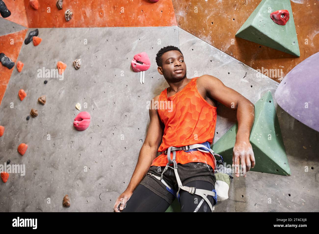 jolly african american man posing near rock climbing wall smiling and ...