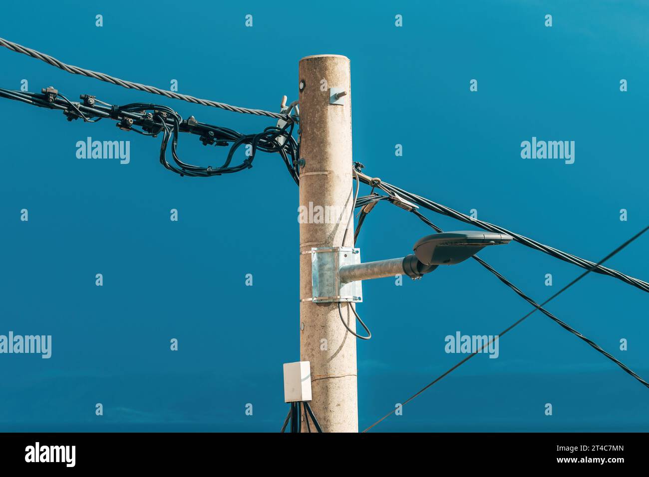 Concrete post with overhead electrical and telephone wires and cables ...