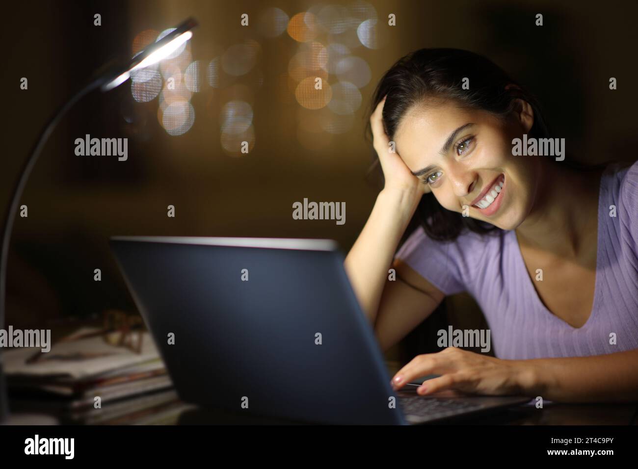 Happy beautiful woman in the night using laptop watching content at ...