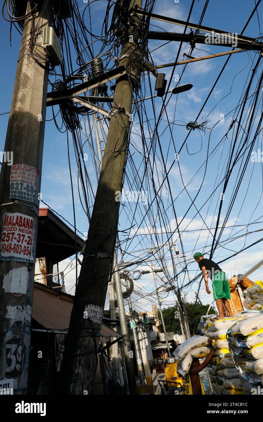 Workers unloading rice bags from a truck with messy cable installations ...