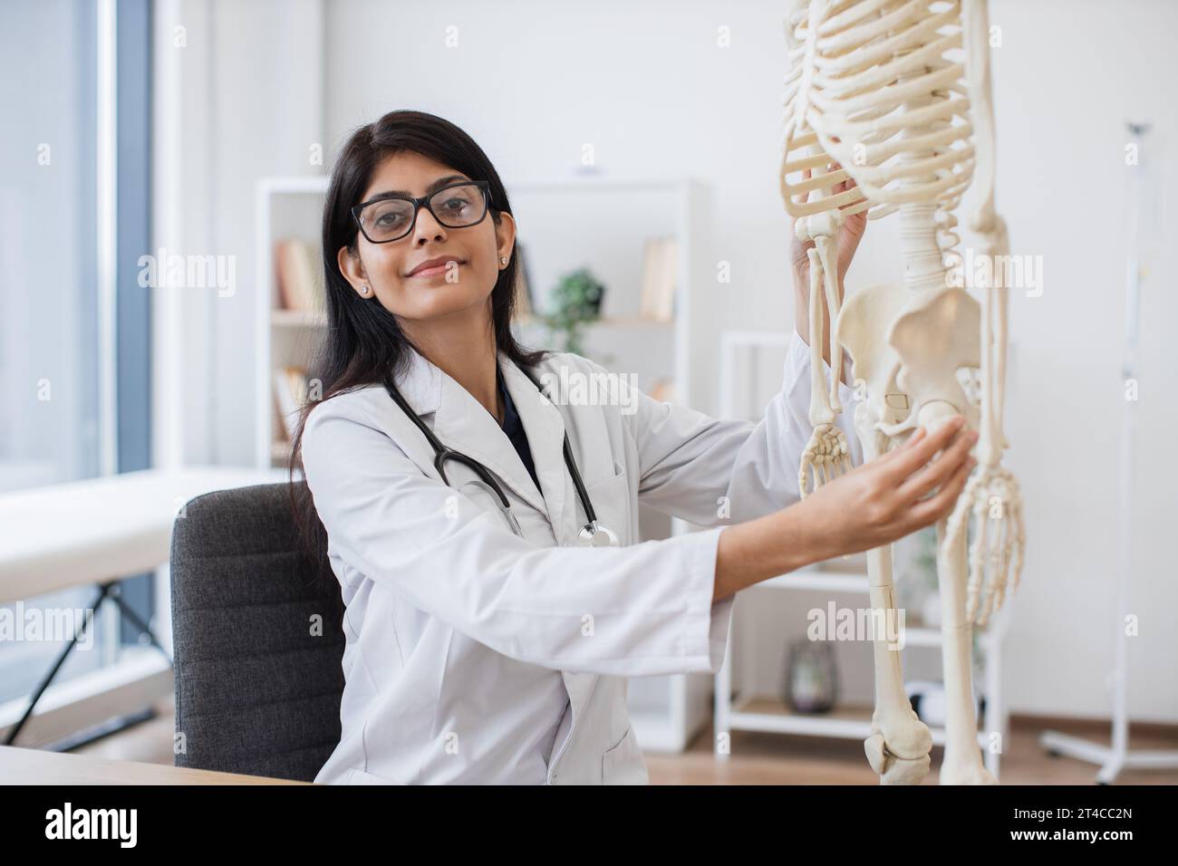 Hospital worker examining bones location on plastic skeleton Stock ...