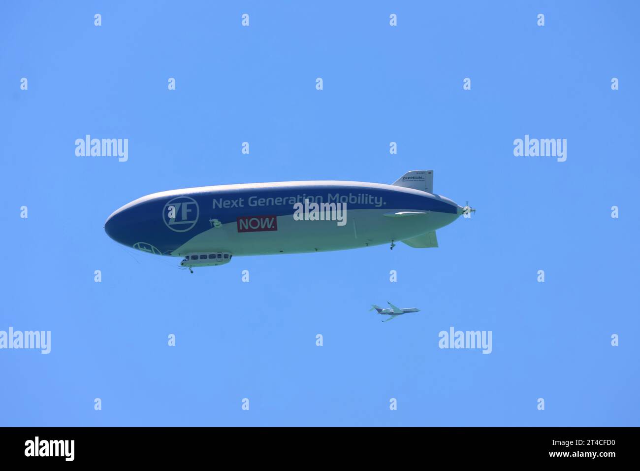 zeppelin in flight in the blue sky, airplane in the background, Lake ...