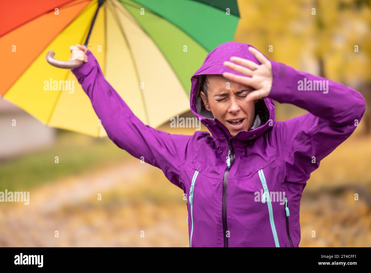 A young woman with an umbrella in a rain jacket wears a hood and ...