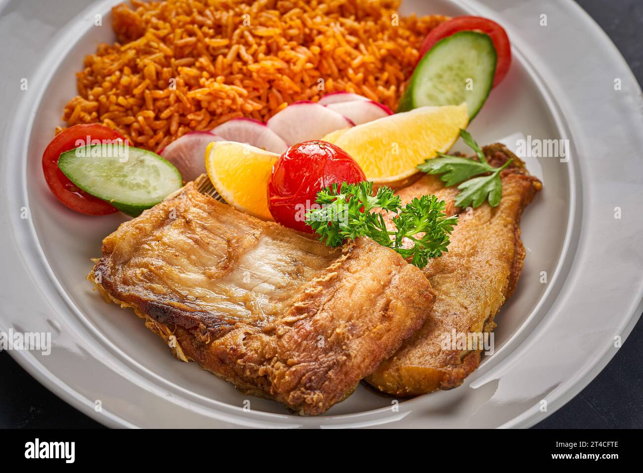 A close-up of A dish of fried fish with rice and vegetables Stock Photo ...