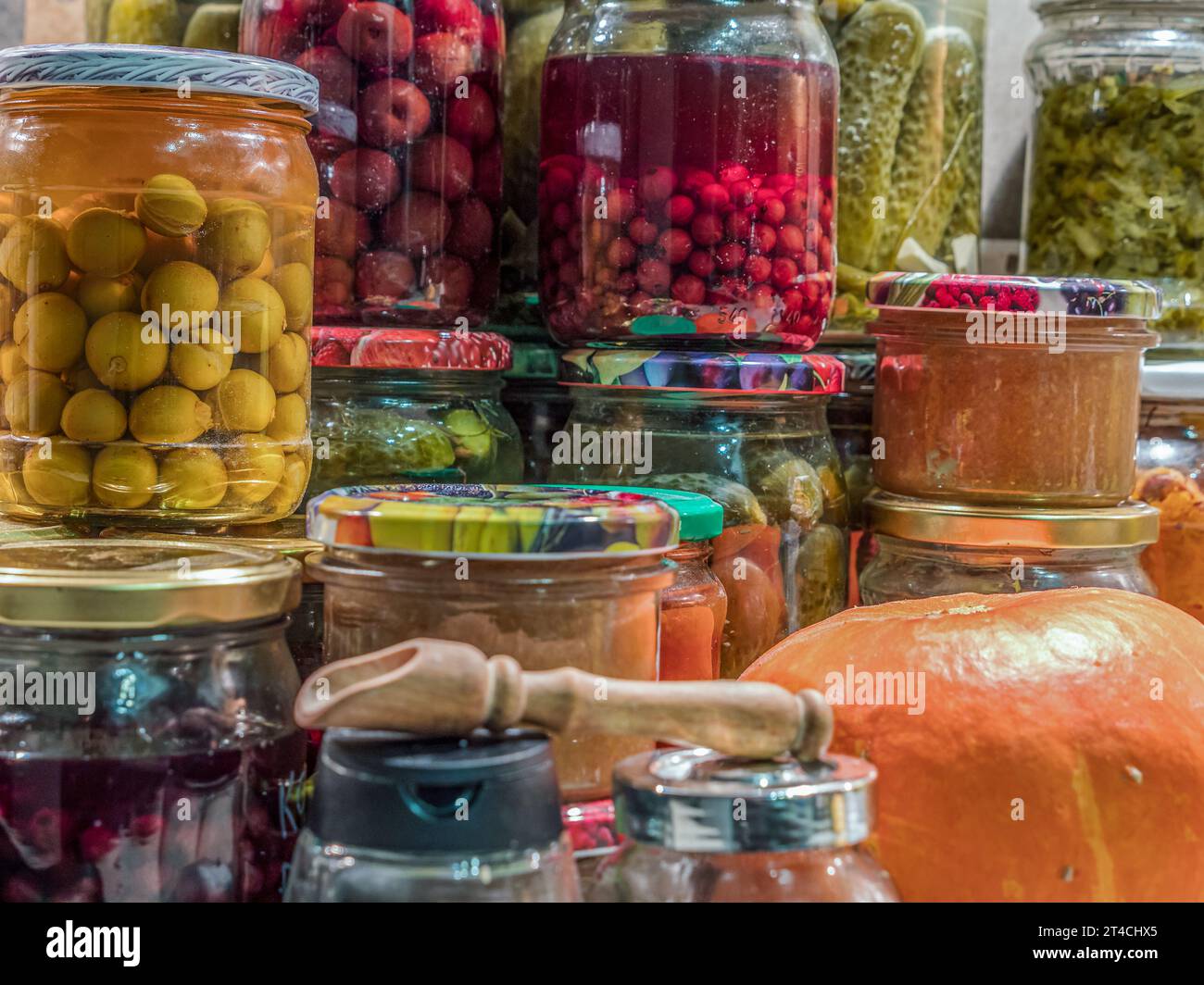 Assorted fruit and vegetable preserves in jars stacked on kitchen ...