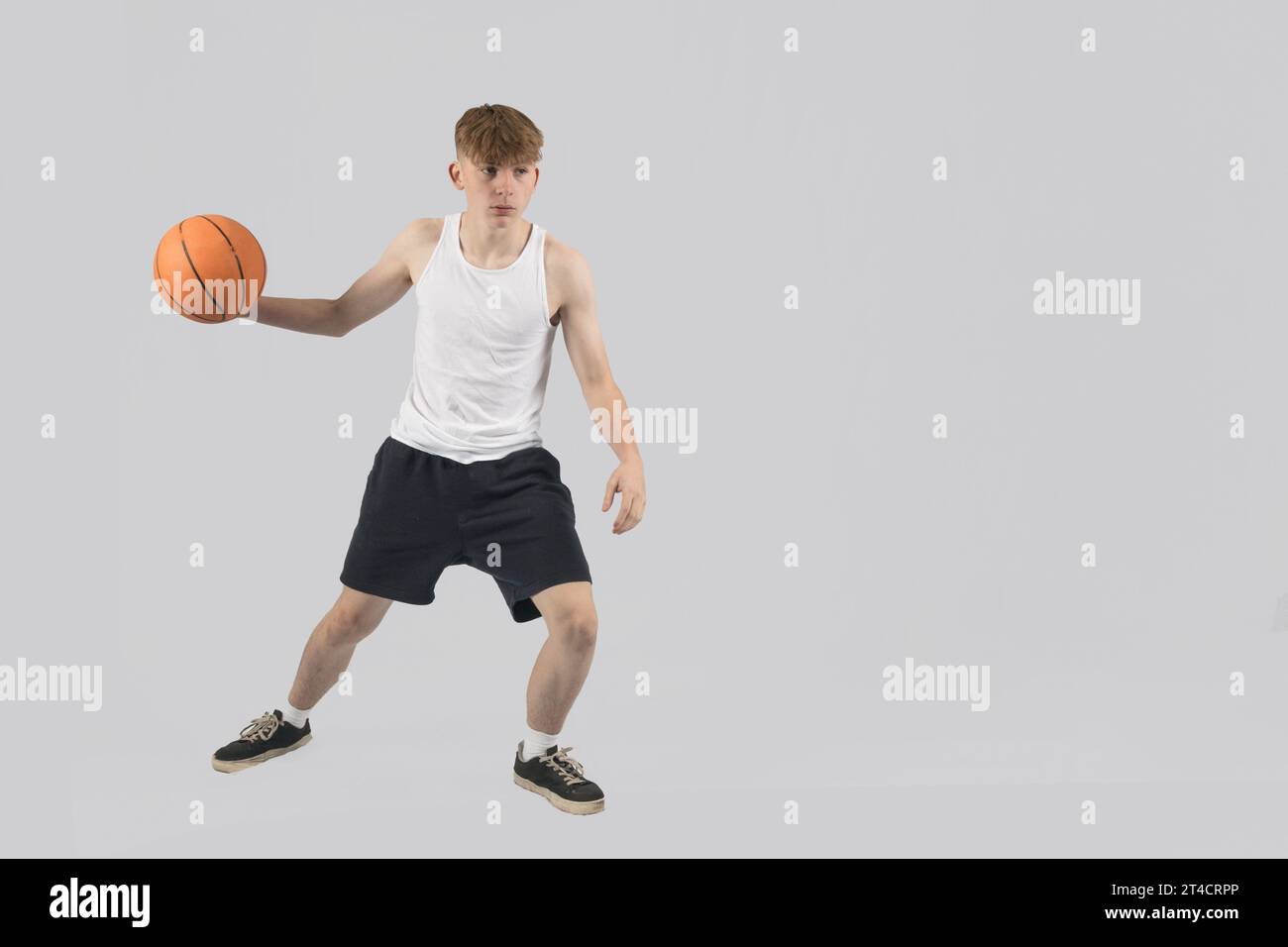 Caucasian teenage boy moving while playing basketball Stock Photo - Alamy