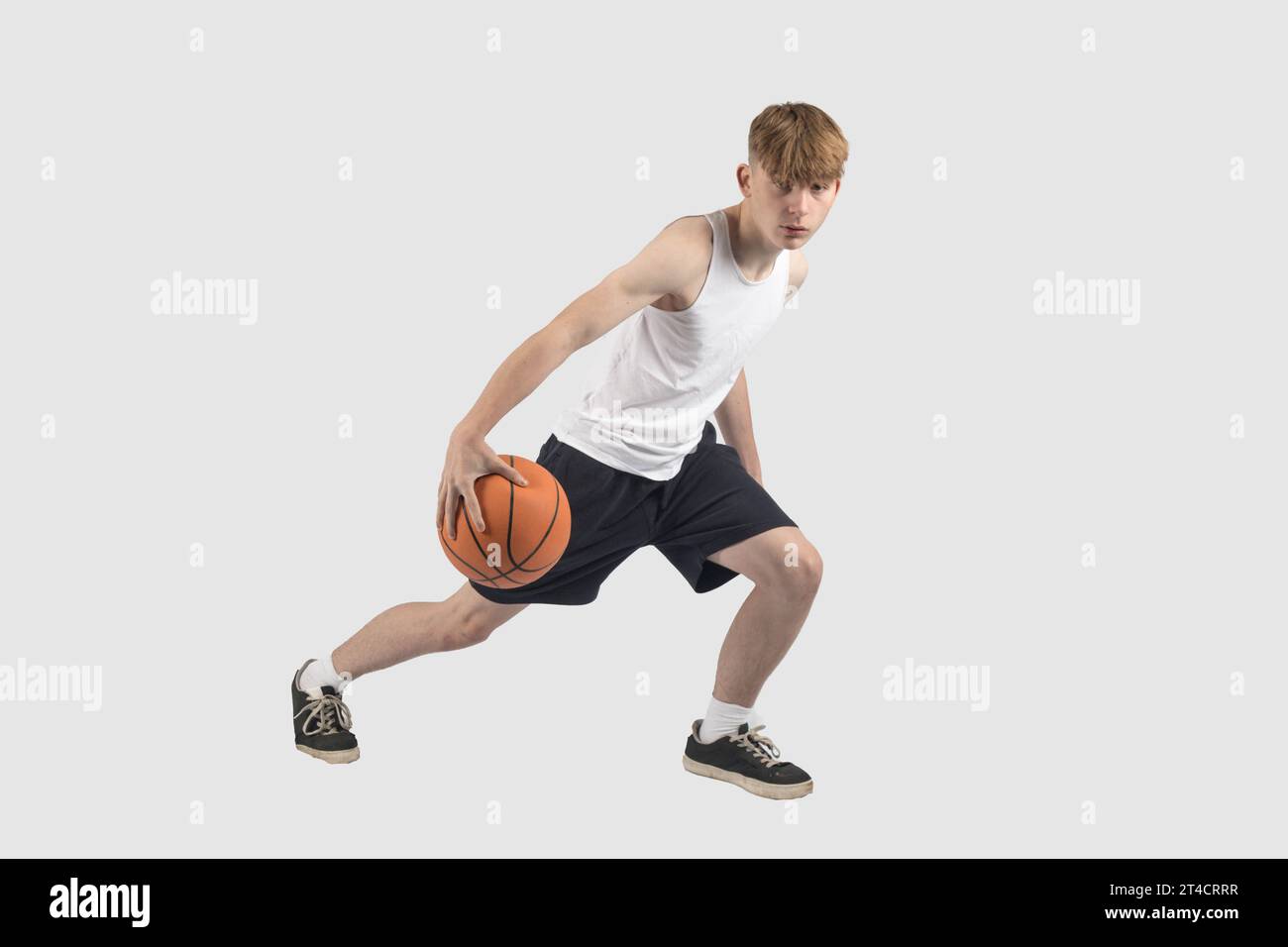 Caucasian teenage boy moving while playing basketball Stock Photo - Alamy