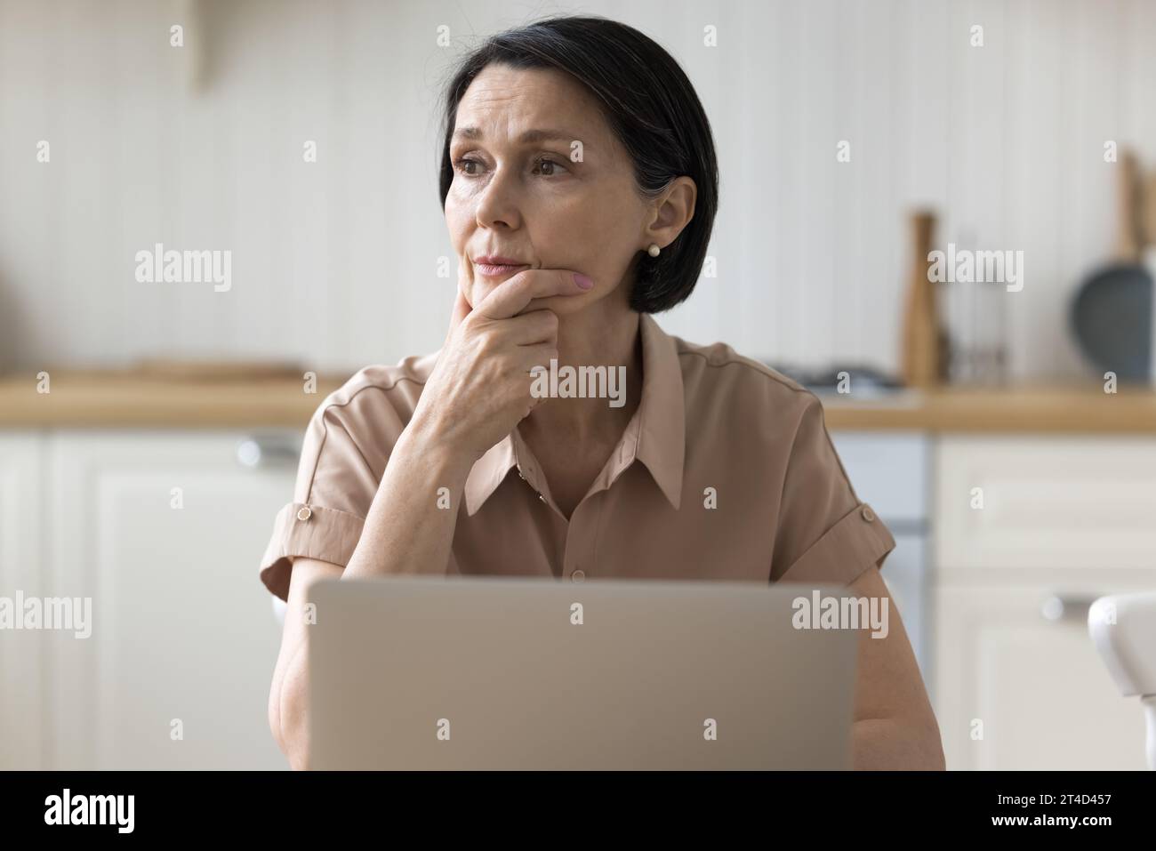 Brooding woman deep in thought sit at table with laptop Stock Photo - Alamy