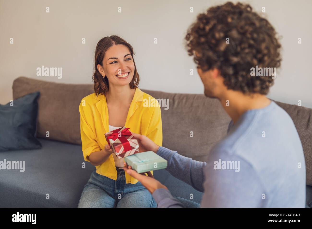 Portrait of young happy couple. Woman is giving gift to her man Stock ...