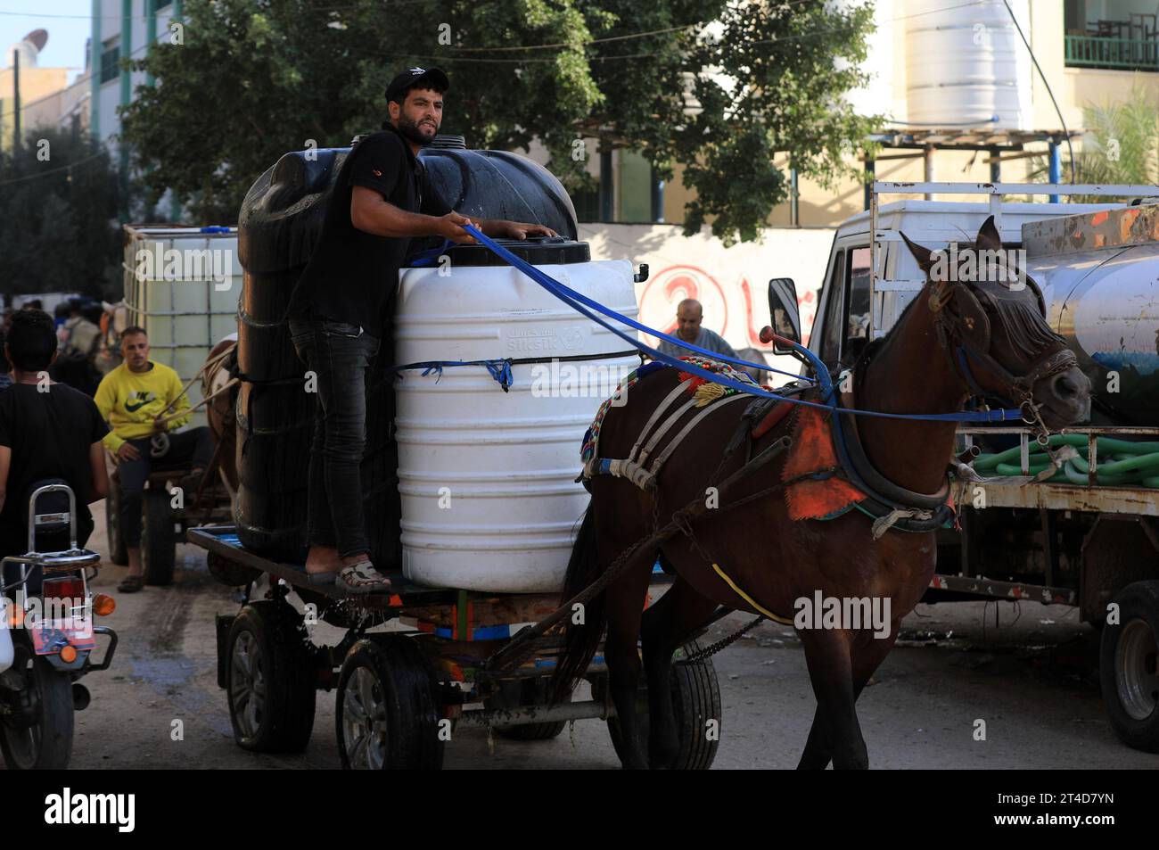 Gaza. 30th Oct, 2023. A man uses donkey-drawn cart to transport water ...