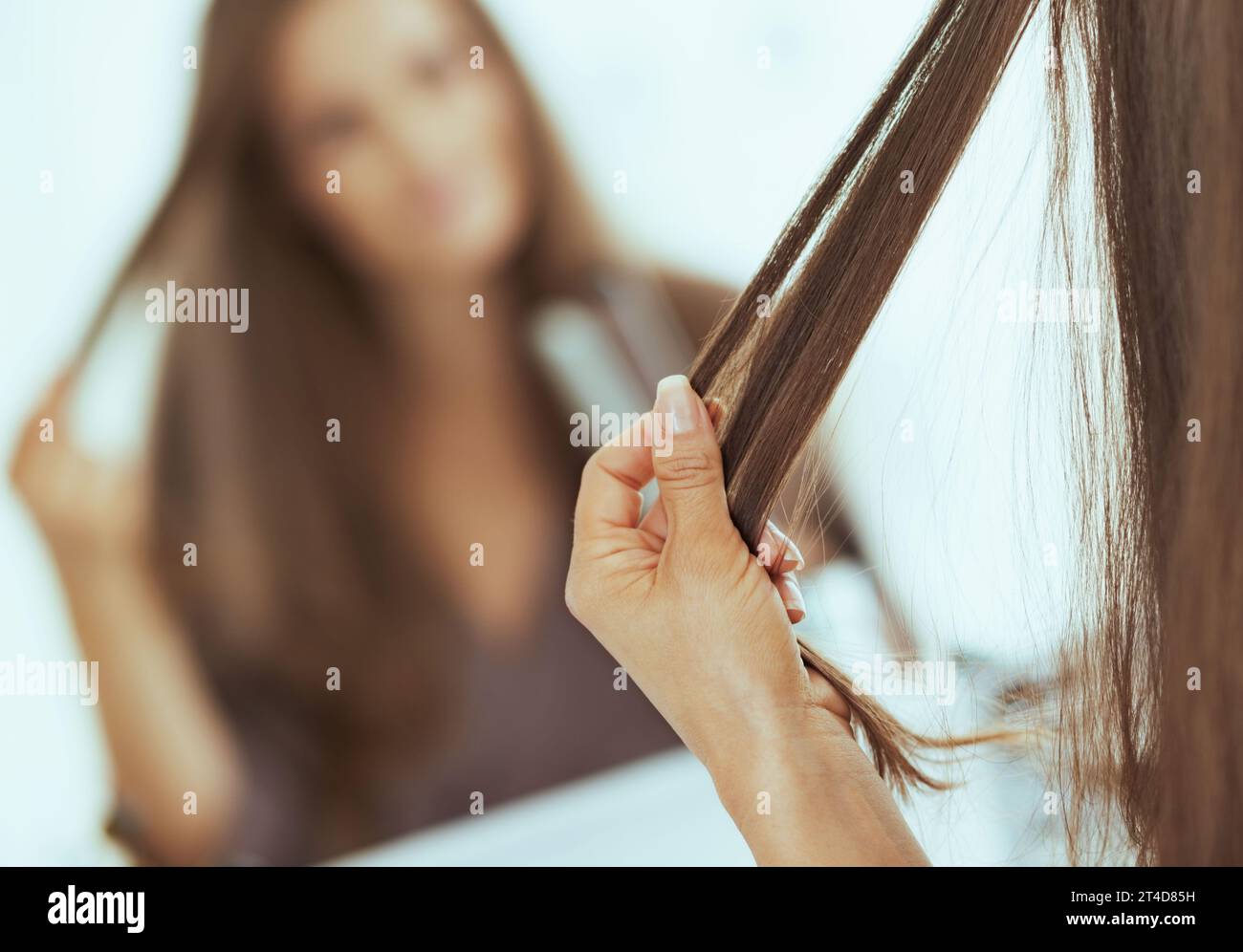 Closeup on woman checking hair after straightening Stock Photo - Alamy
