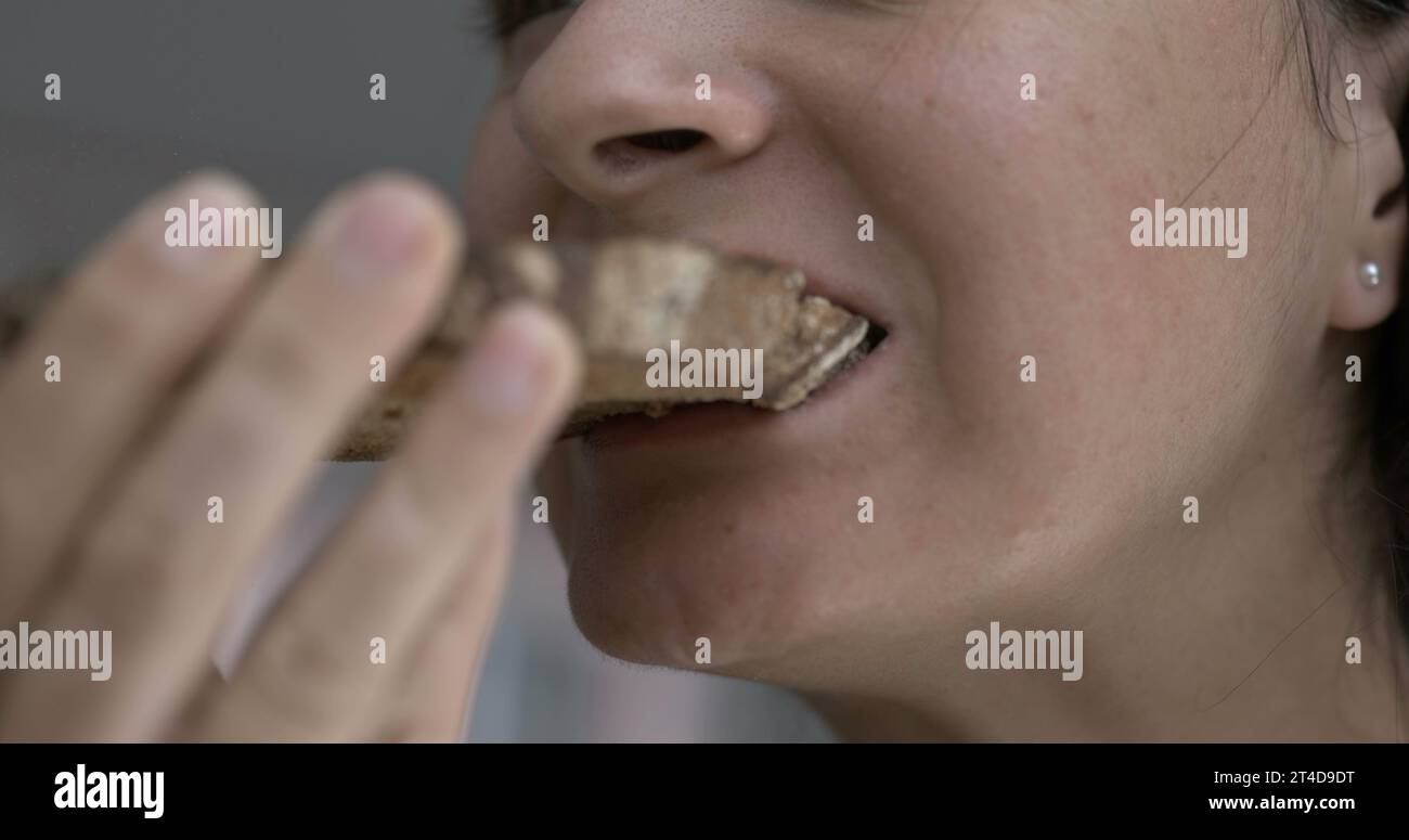Woman close-up mouth taking a bite of toast bread . Person eating carb ...