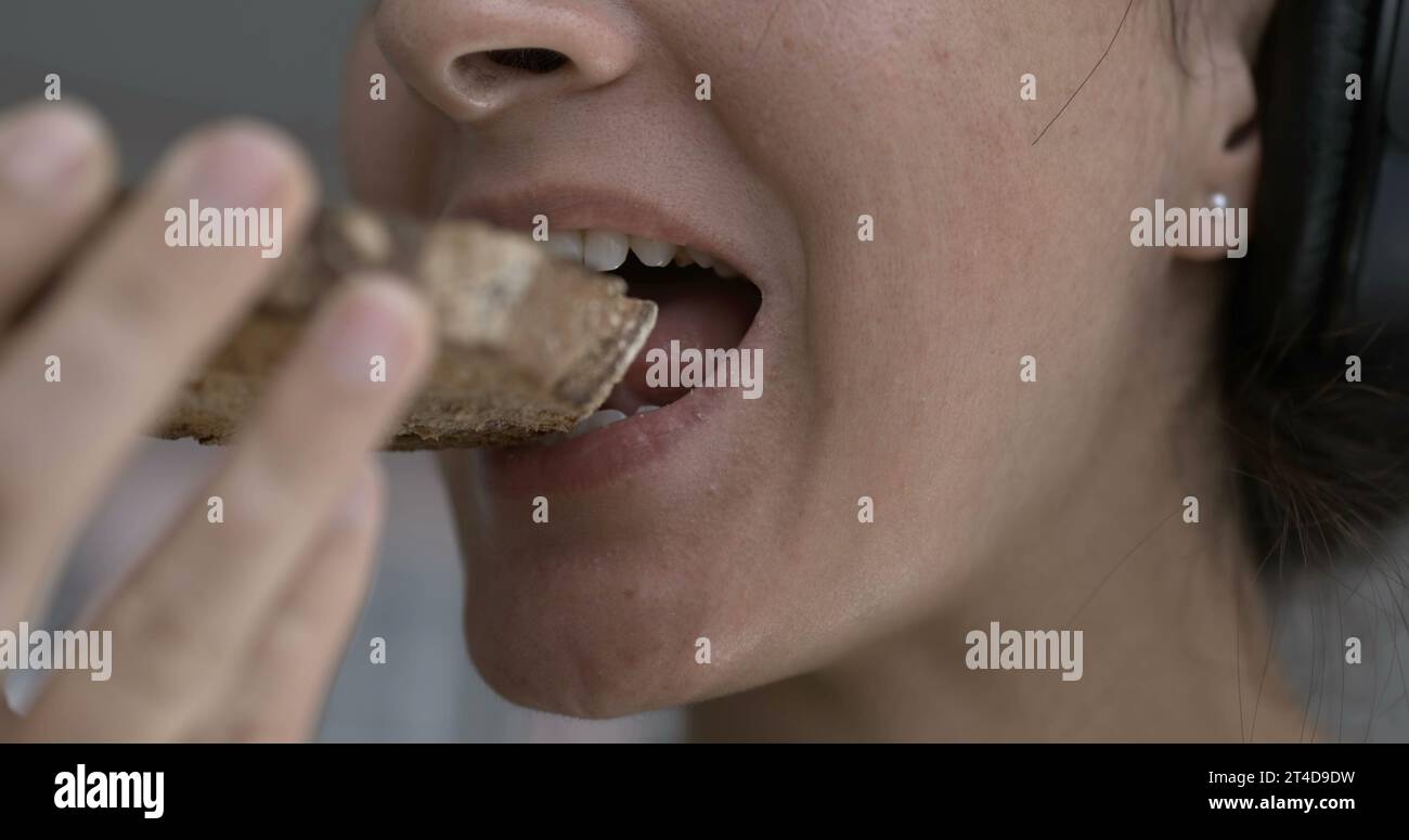 Woman close-up mouth taking a bite of toast bread . Person eating carb ...