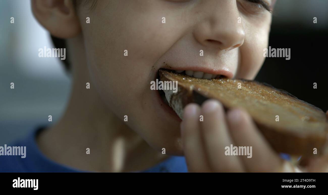 Little boy eating toast bread, close-up child mouth takes a bite of ...