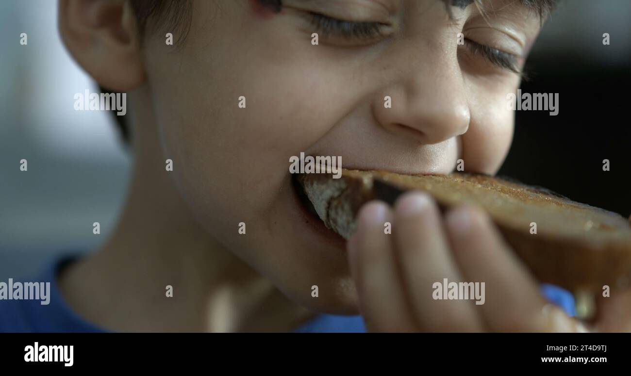 Little boy eating toast bread, close-up child mouth takes a bite of ...