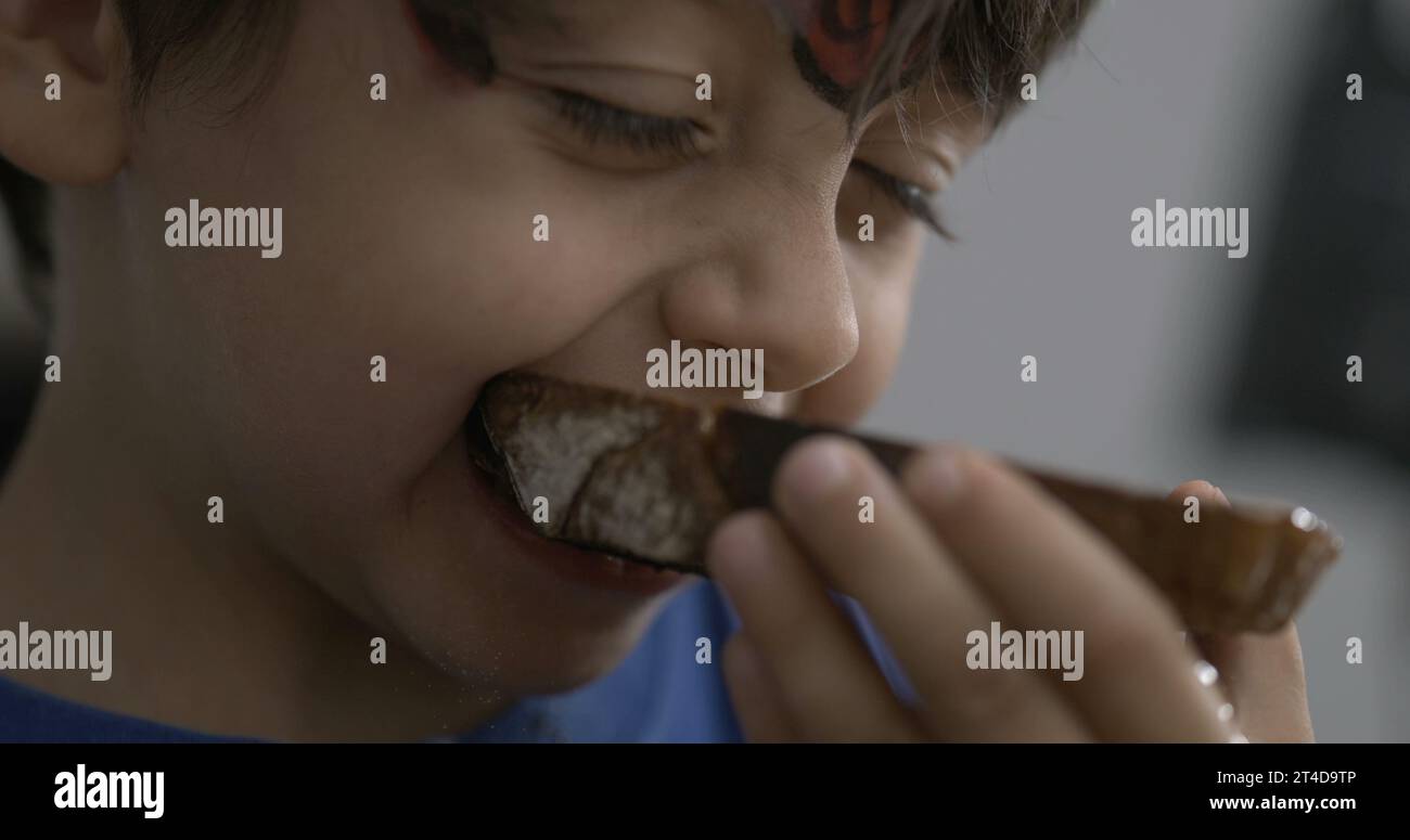 One small boy taking a bite of toast bread, close-up child mouth eating ...