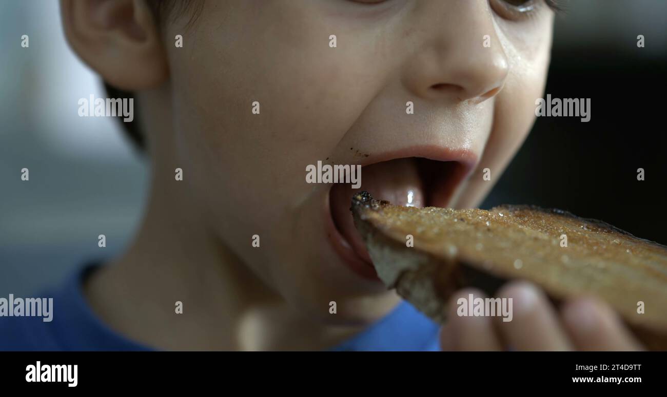 Little boy eating toast bread, close-up child mouth takes a bite of ...