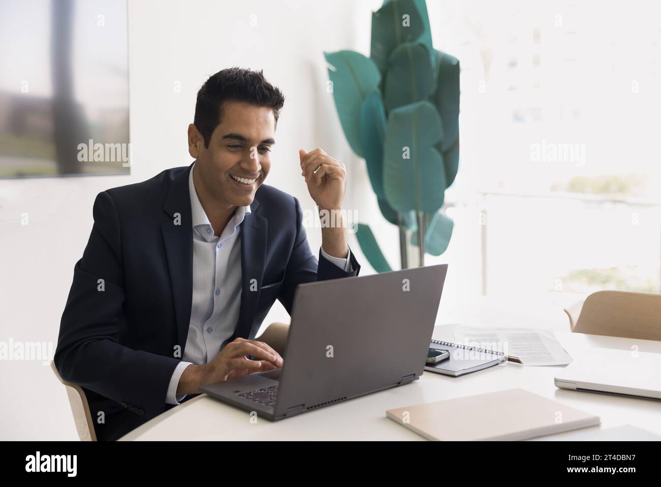 Happy successful Indian businessman using Internet service on laptop ...