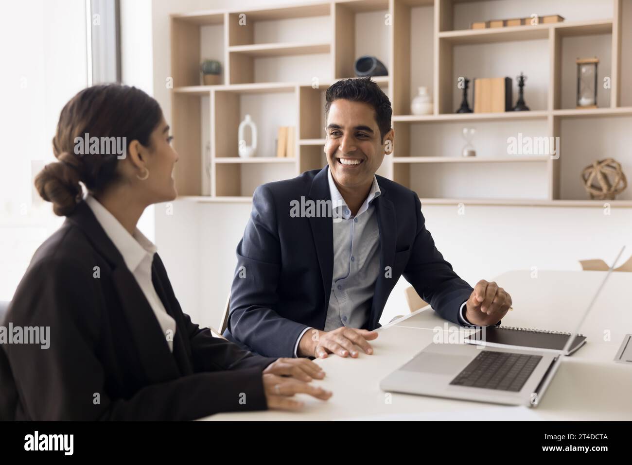 Cheerful manager and client discussing successful cooperation at laptop ...