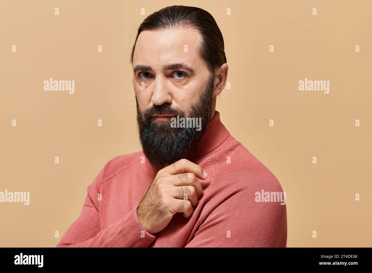 portrait of good looking serious man with beard posing in pink ...