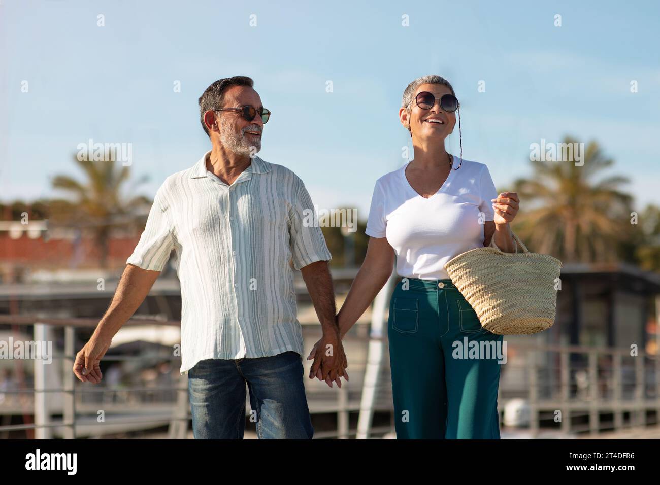 Senior romantic spouses holding hands posing at dock with sailboats ...