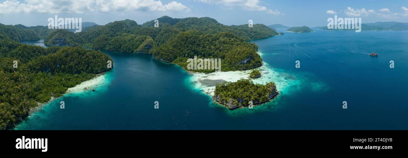 Limestone islands, covered by rainforest, are fringed by coral reefs in ...
