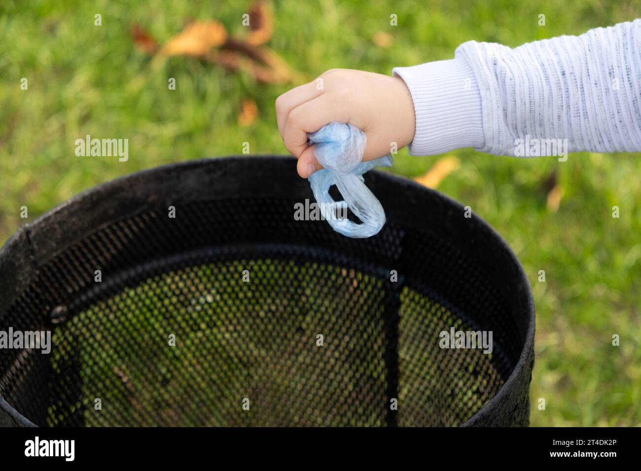 A child throws a plastic bag in the trash. Concept of garbage recycling ...