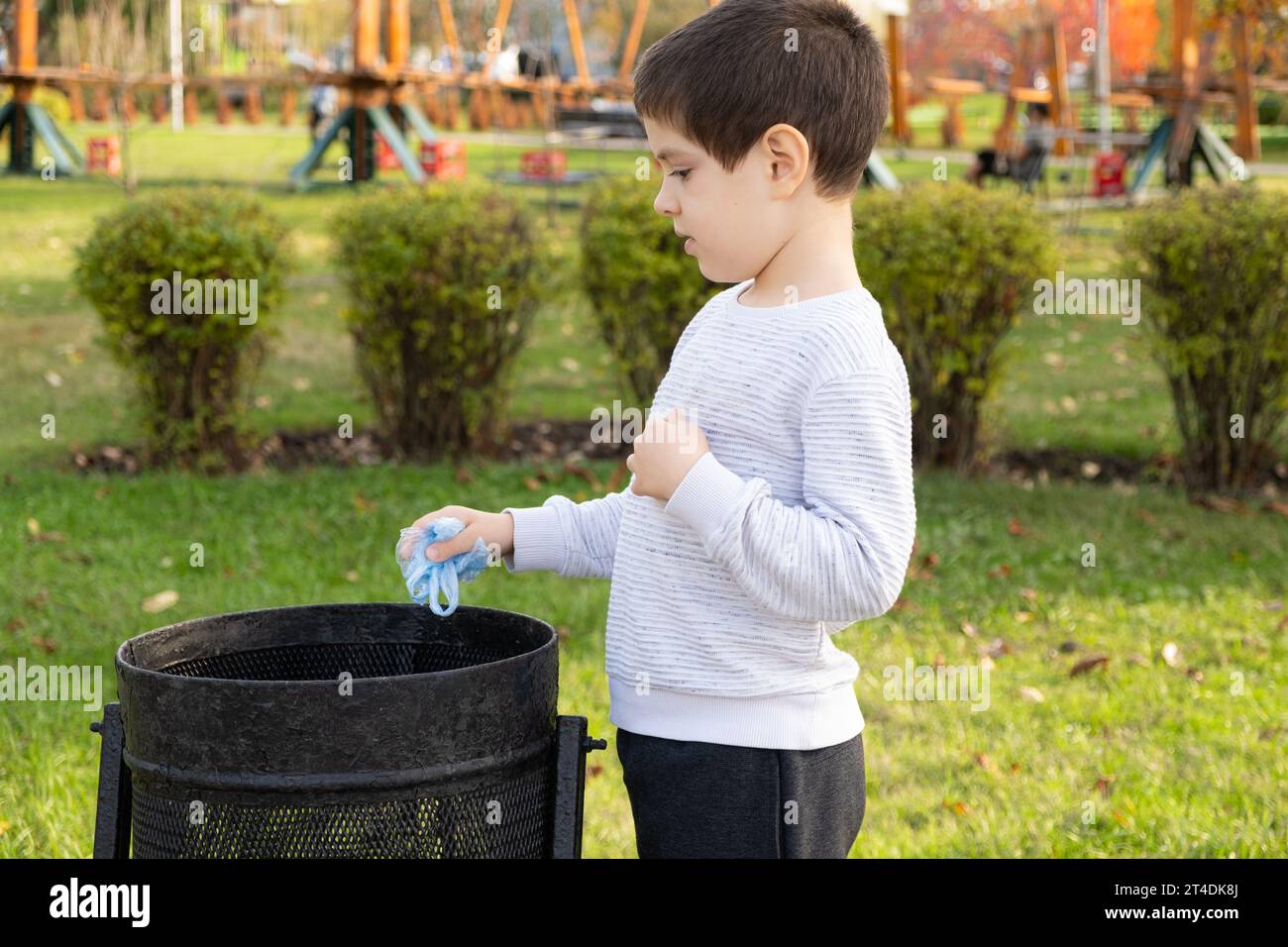 A child throws a plastic bag in the trash. Concept of garbage recycling ...
